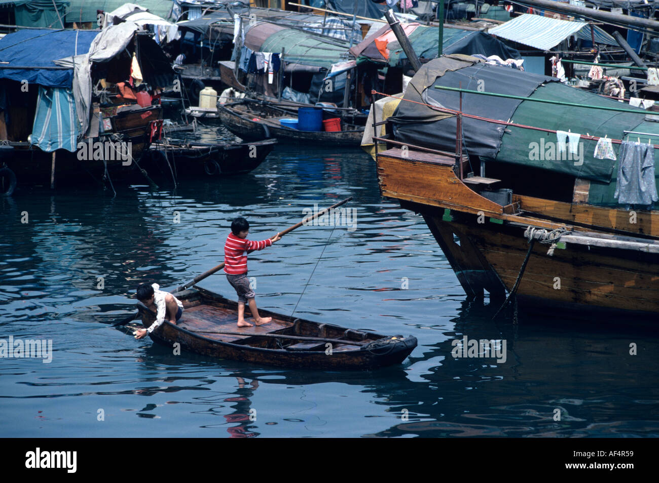 Two small children on a small traditional junk one holding the stern ...