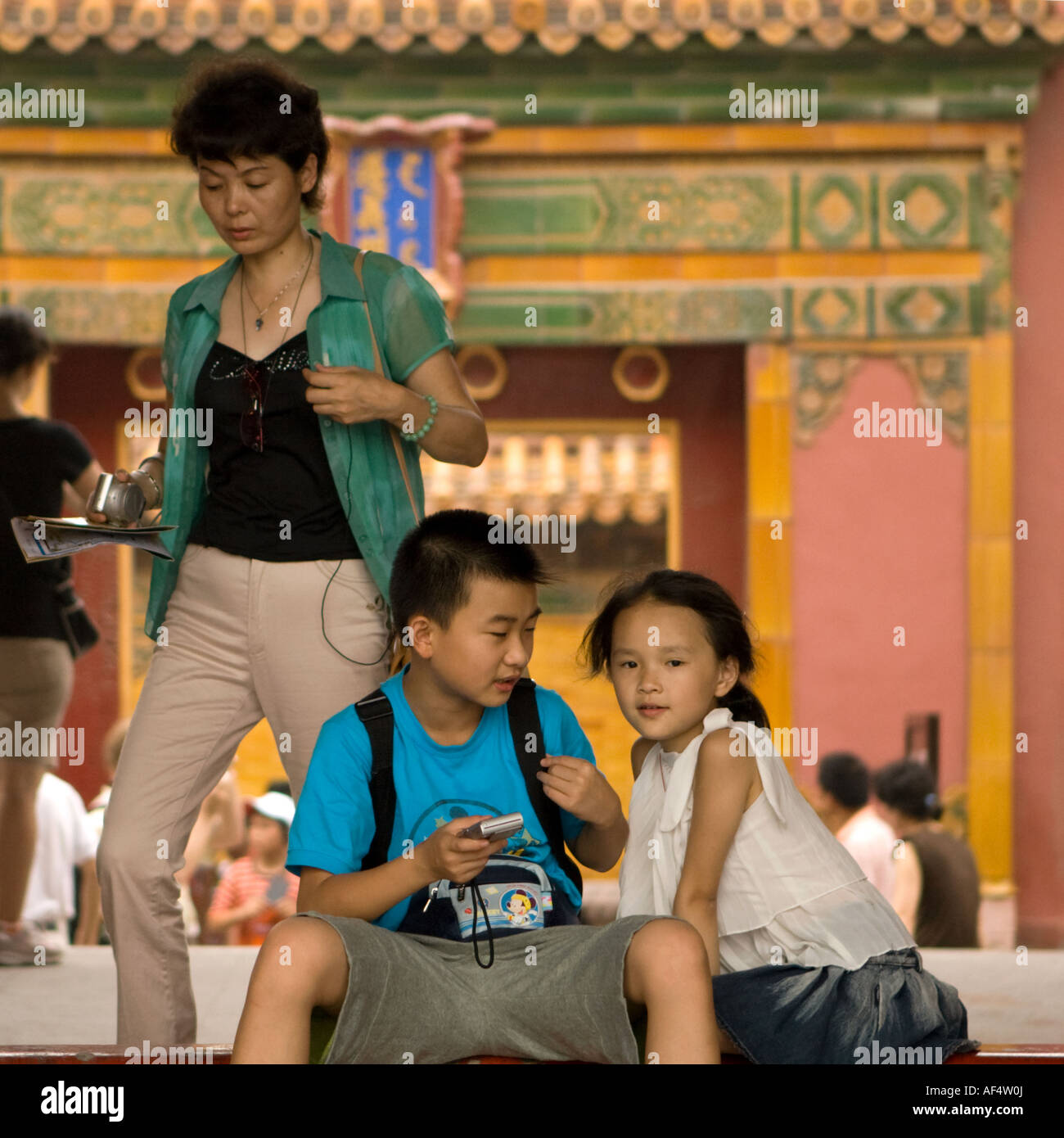 Young Chinese brother and sister sitting in gateway of Forbidden City ...