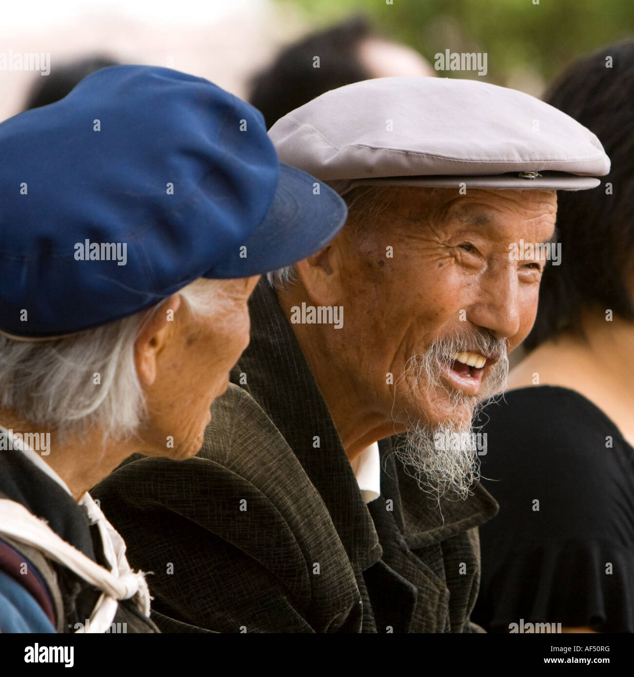 Elderly ethnic Naxi Chinese man laughing and sharing a joke with his ...