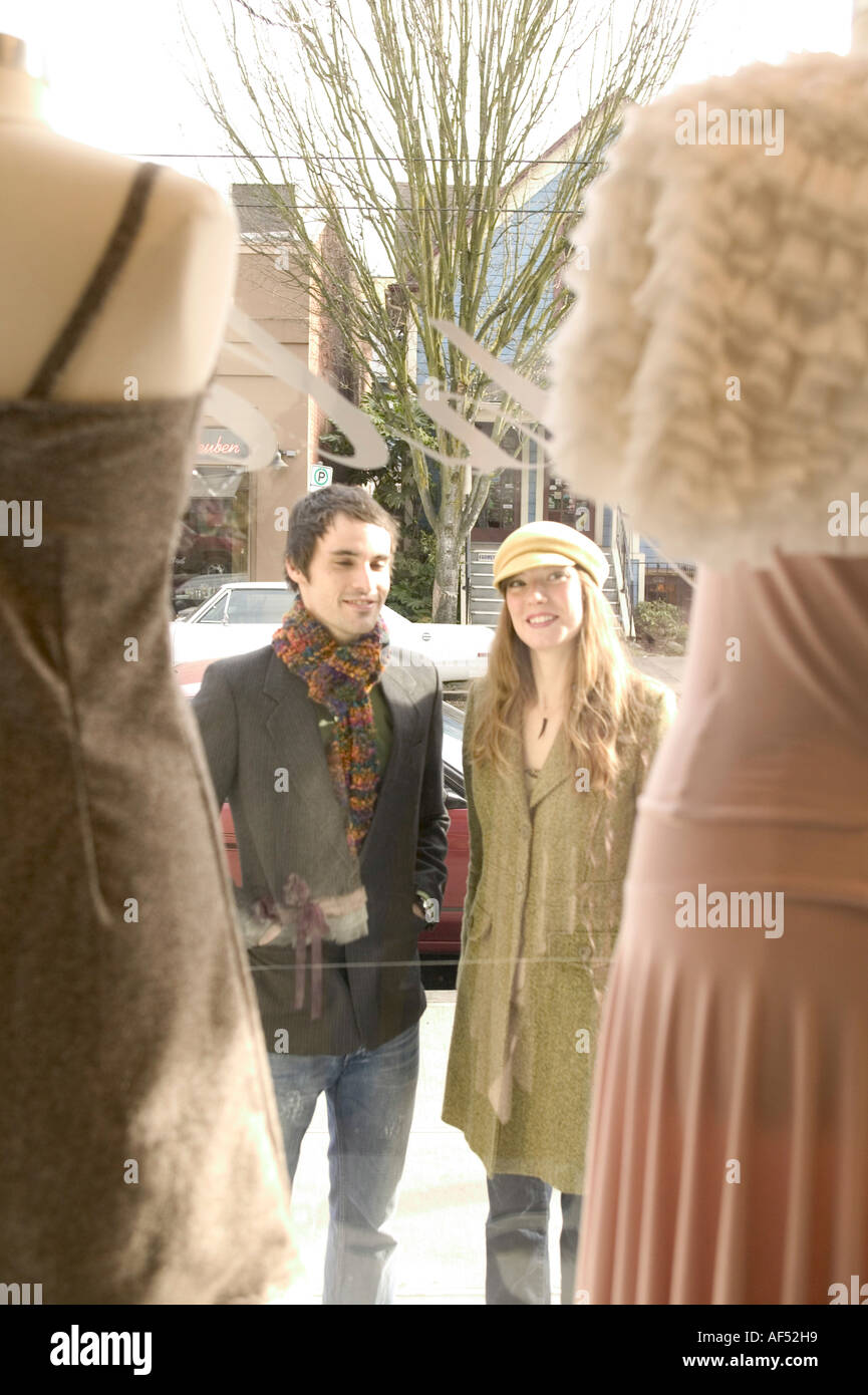 Young couple looking at mannequins in a window display Stock Photo - Alamy
