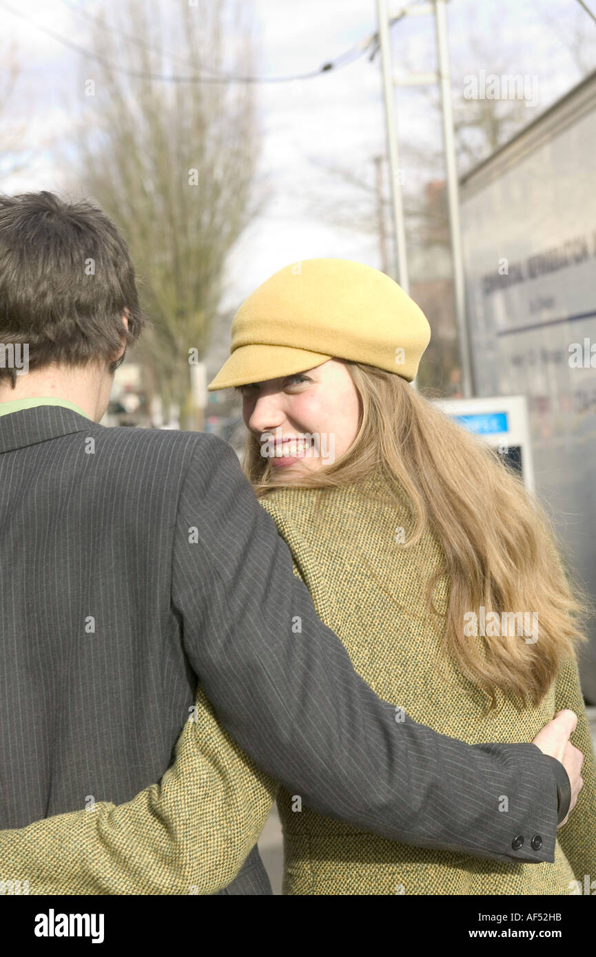 Rear view of a young couple walking with their arms around each other ...