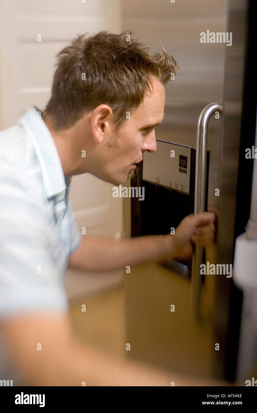Side profile of a mid adult man opening a refrigerator door Stock Photo ...