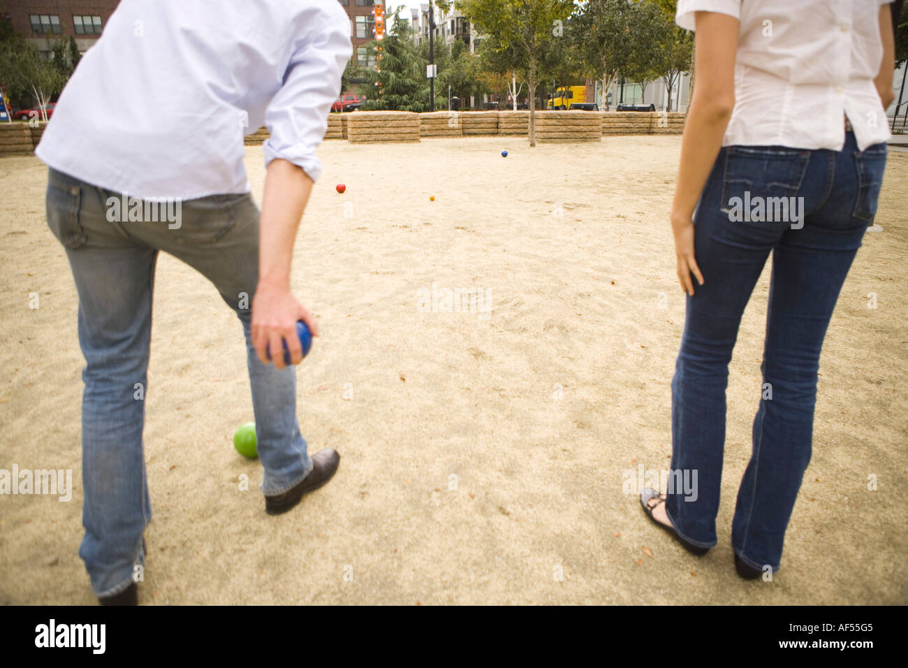 Rear view of a man throwing a ball with a woman standing beside him ...