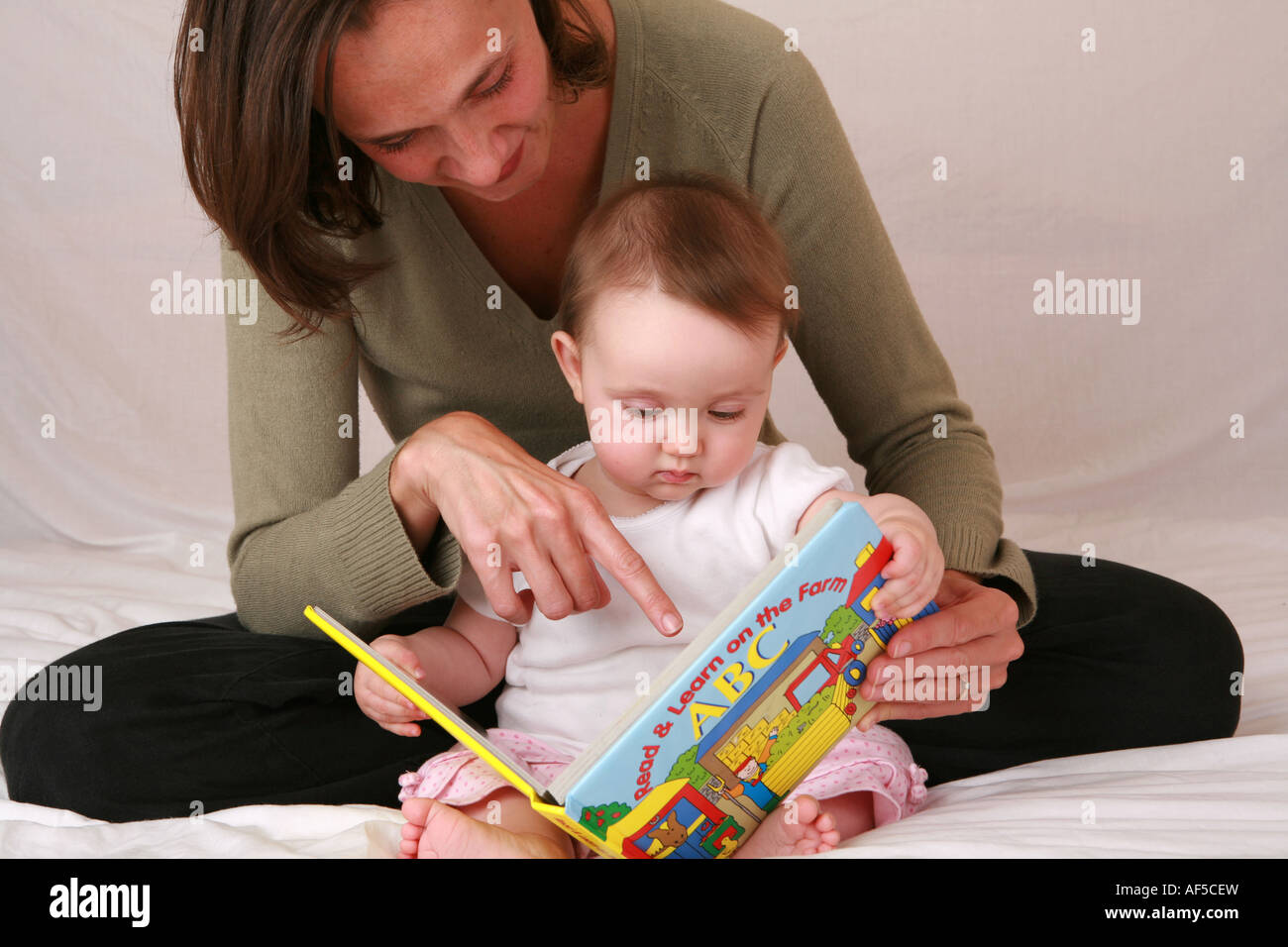 Young child infant baby sitting upright and reading learning playing ...