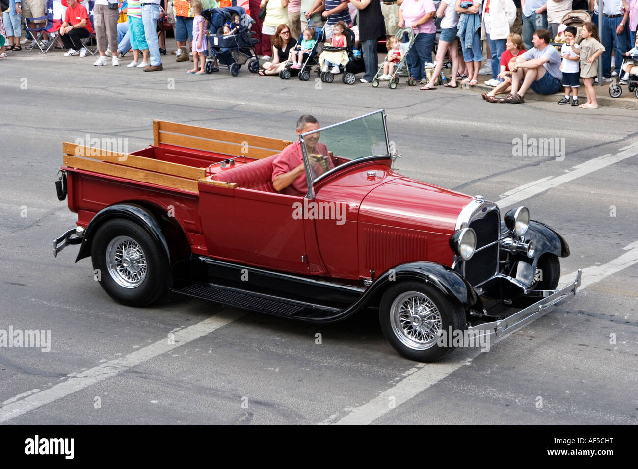 Antique red Ford Model-A pickup truck driving in street festival parade ...