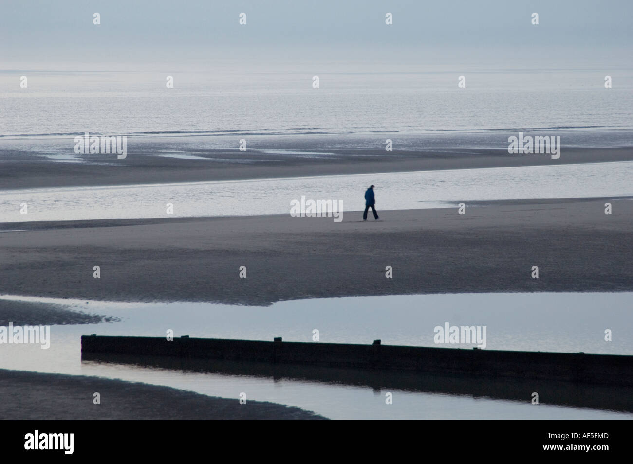 single lone human being walking along beach cold feeling cold blue ...