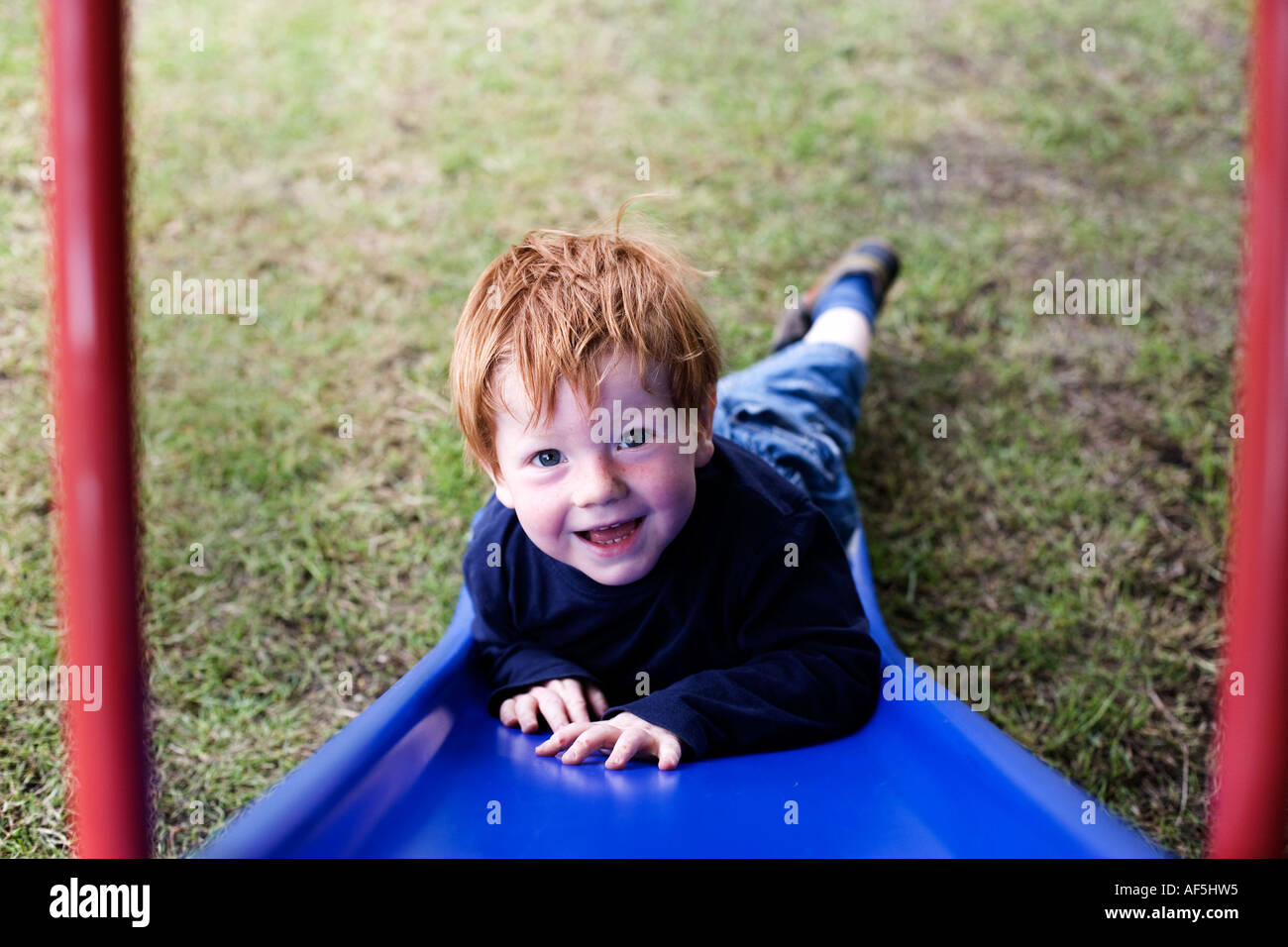 Boy playing on slide Stock Photo - Alamy