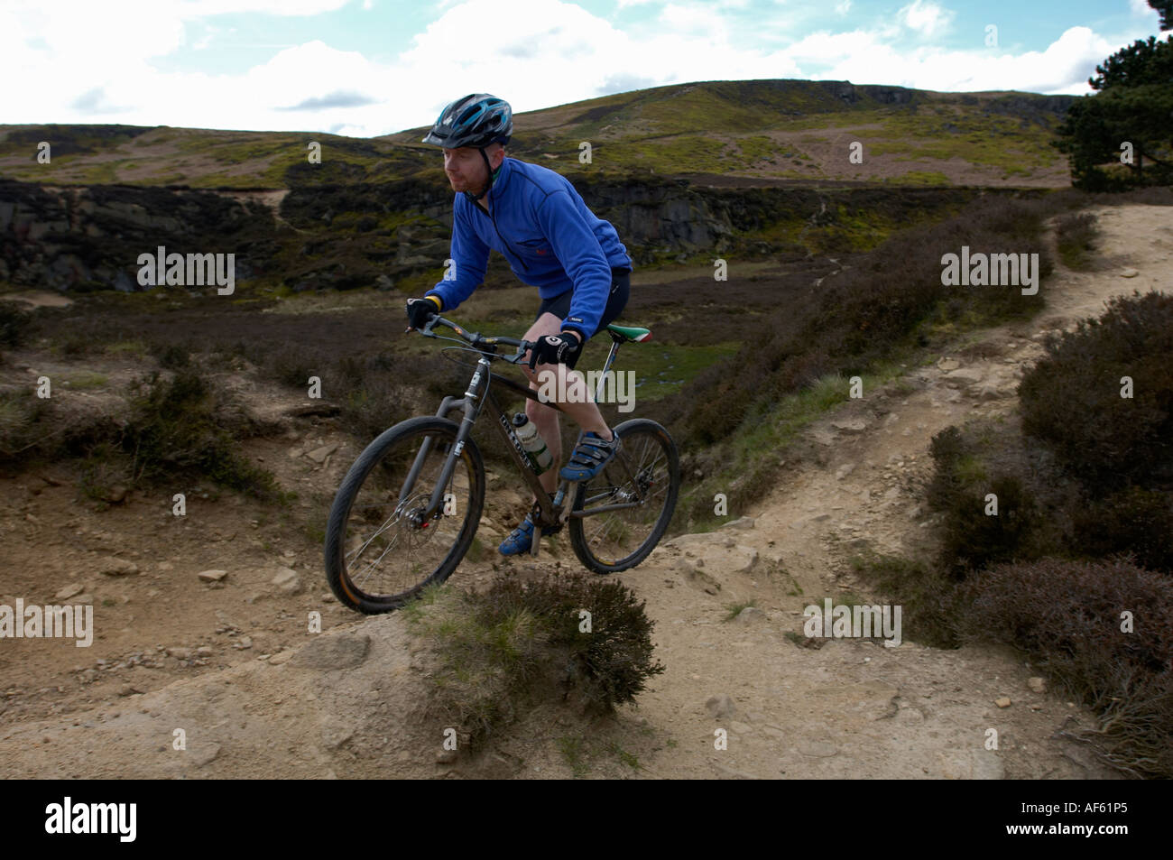 man in rural mountain dale type landscape on and riding a mountain bike ...