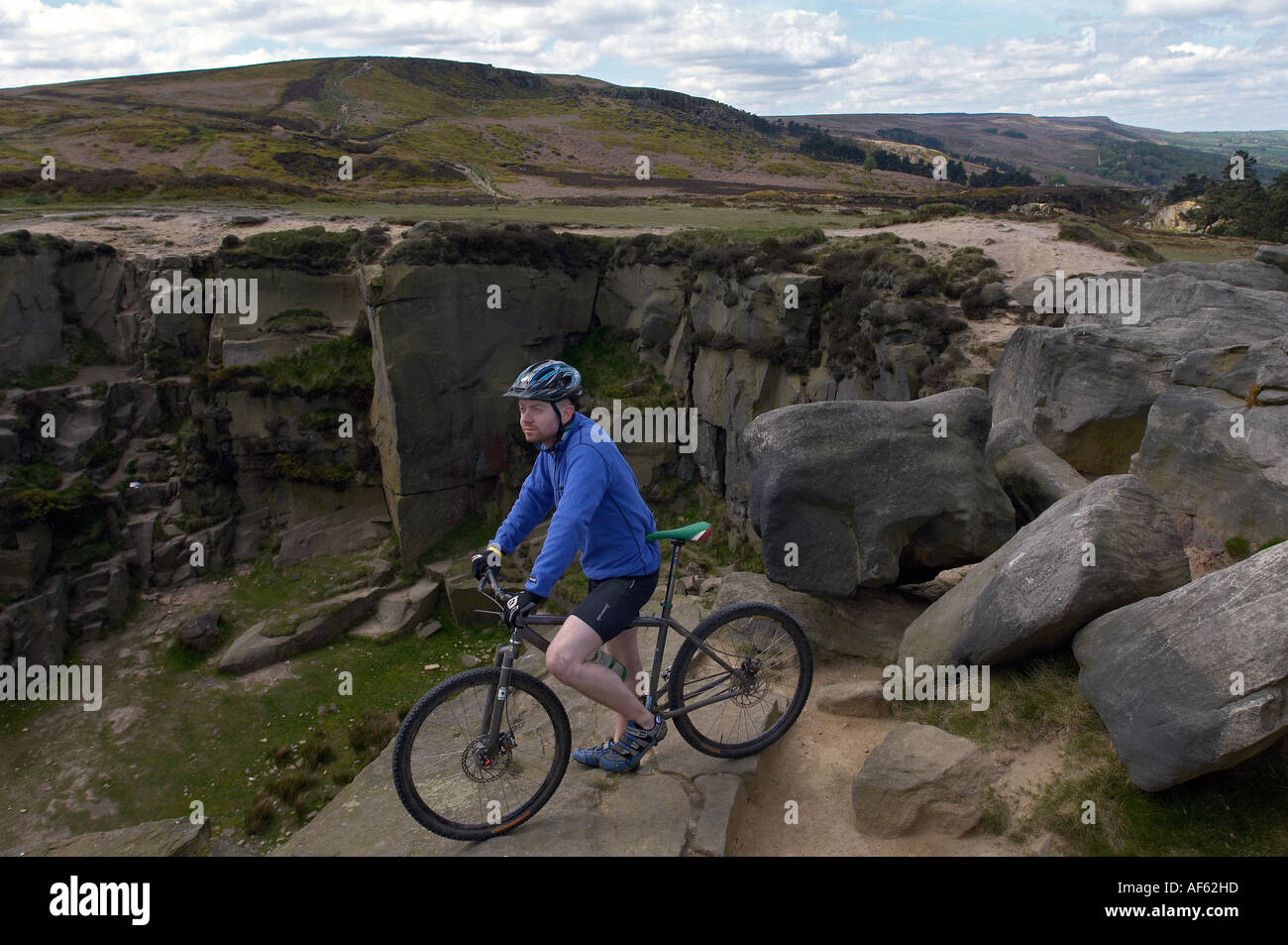 man in rural mountain dale type landscape on and riding a mountain bike ...