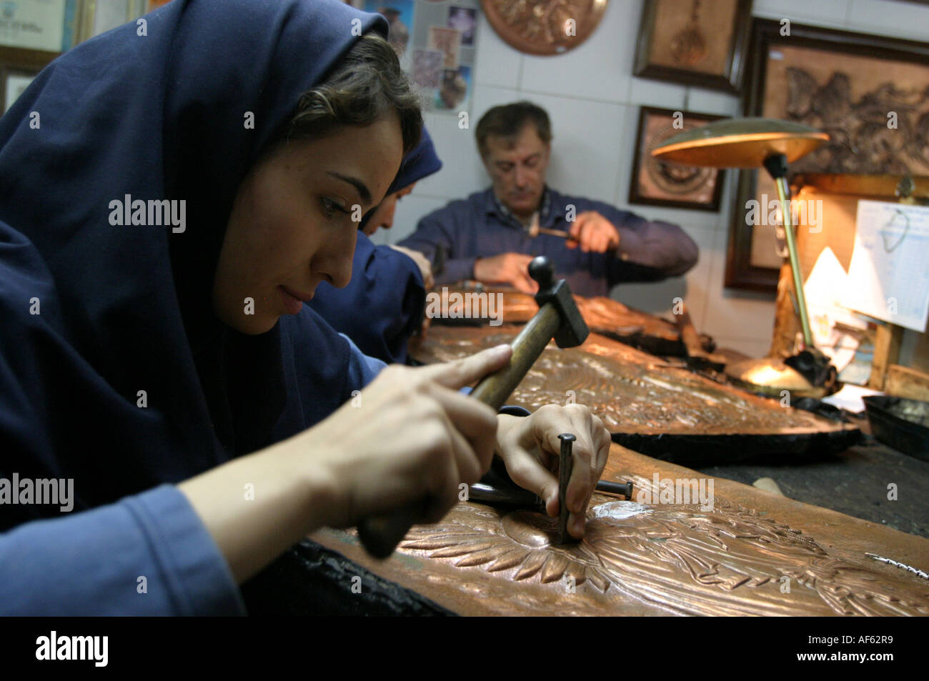 Craftswomen work on copper in a studio in the Iranian city of Isfahan ...
