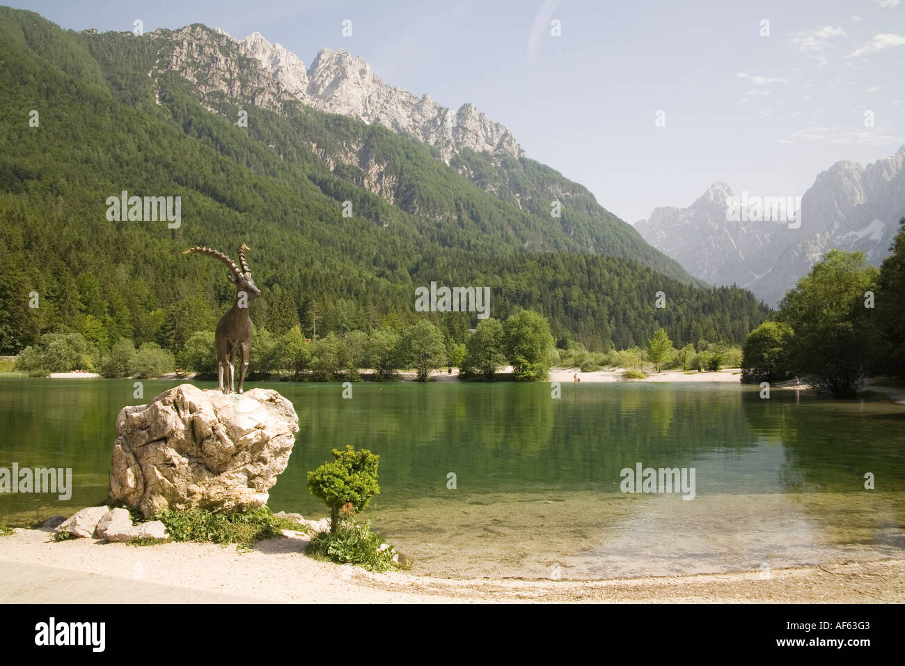 SLOVENIA EU June The Ibex statue at Lake Jasna with the Julian Alps in ...