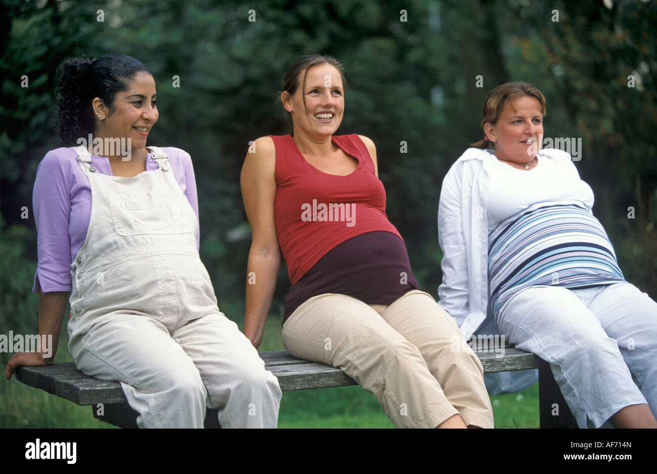 Three pregnant women sitting on a bench outside Stock Photo - Alamy