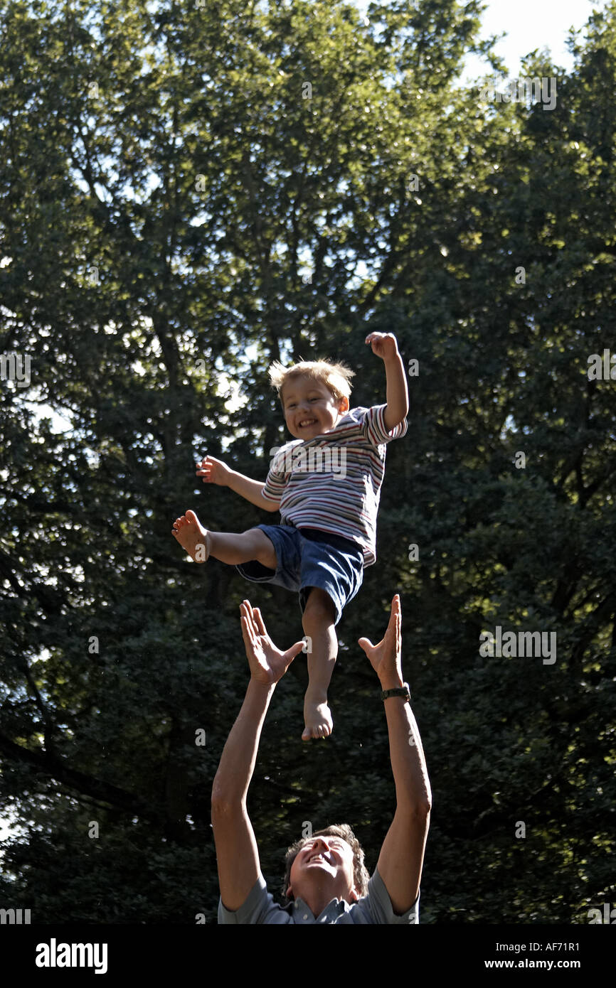 Young boy child laughing being thrown into the air and caught by father ...