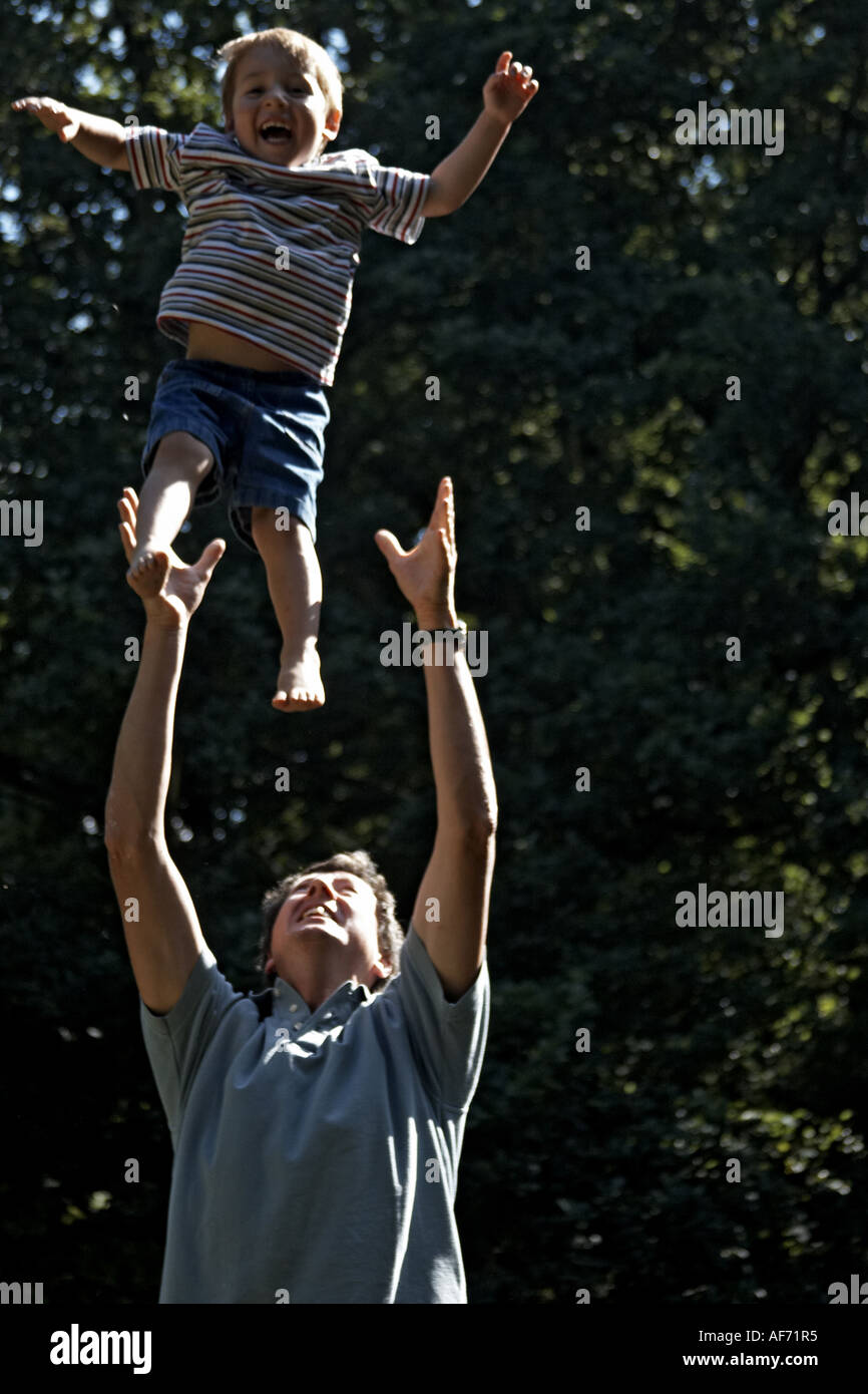 Young boy child laughing being thrown into the air and caught by father ...