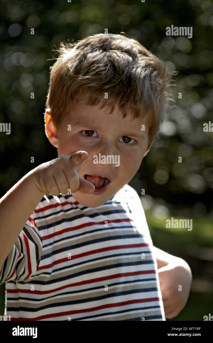Young boy child pointing with an accusing expression outdoors in woods ...