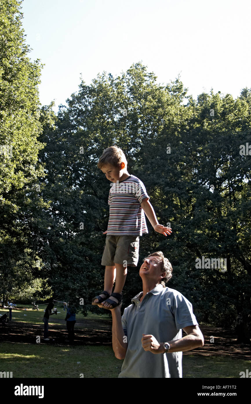 Young boy child balancing like acrobat on hand of father man outdoors ...