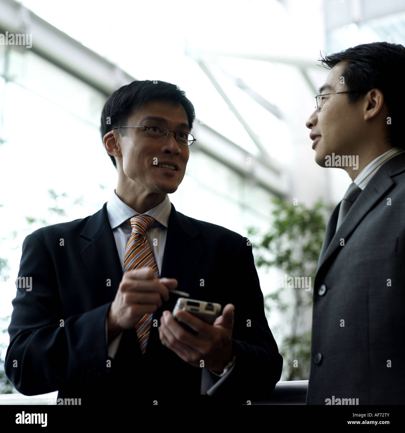 Two business people consulting PDA together Stock Photo - Alamy