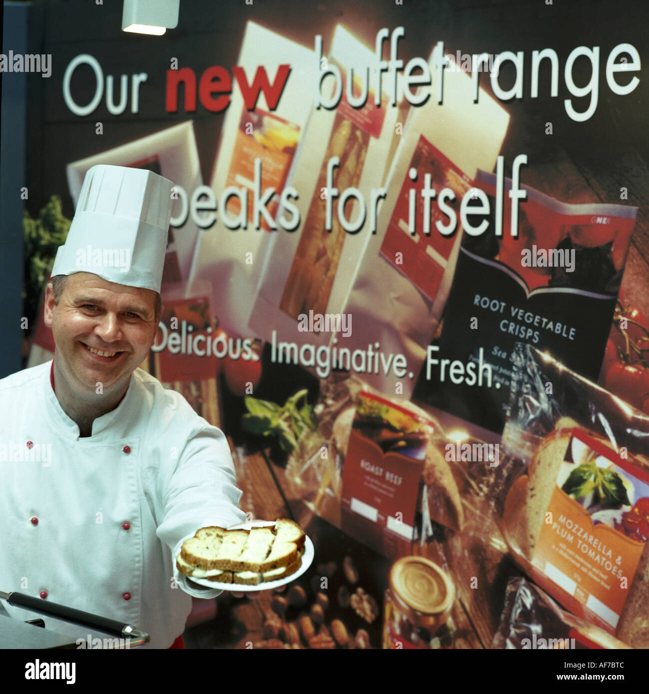 Portrait of chef presenting plate of freshly made sandwich outside shop ...