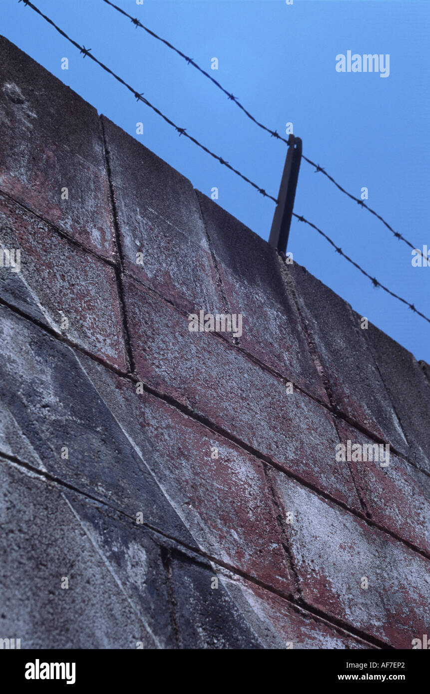 Sharp angled view of wall with barbed wire running along Stock Photo ...