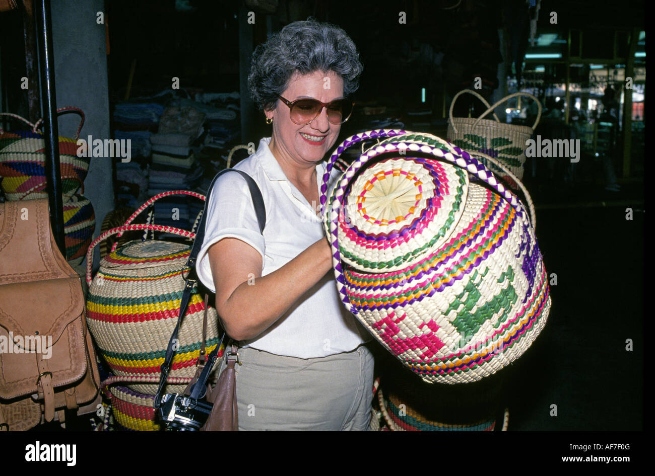 An American tourist examines locally made baskets in a small market in ...