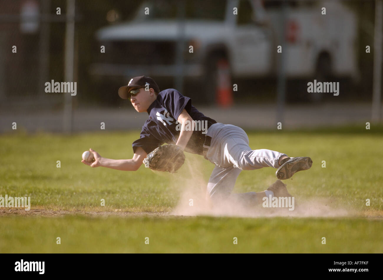 Baseball player throwing ball while falling to side Stock Photo - Alamy