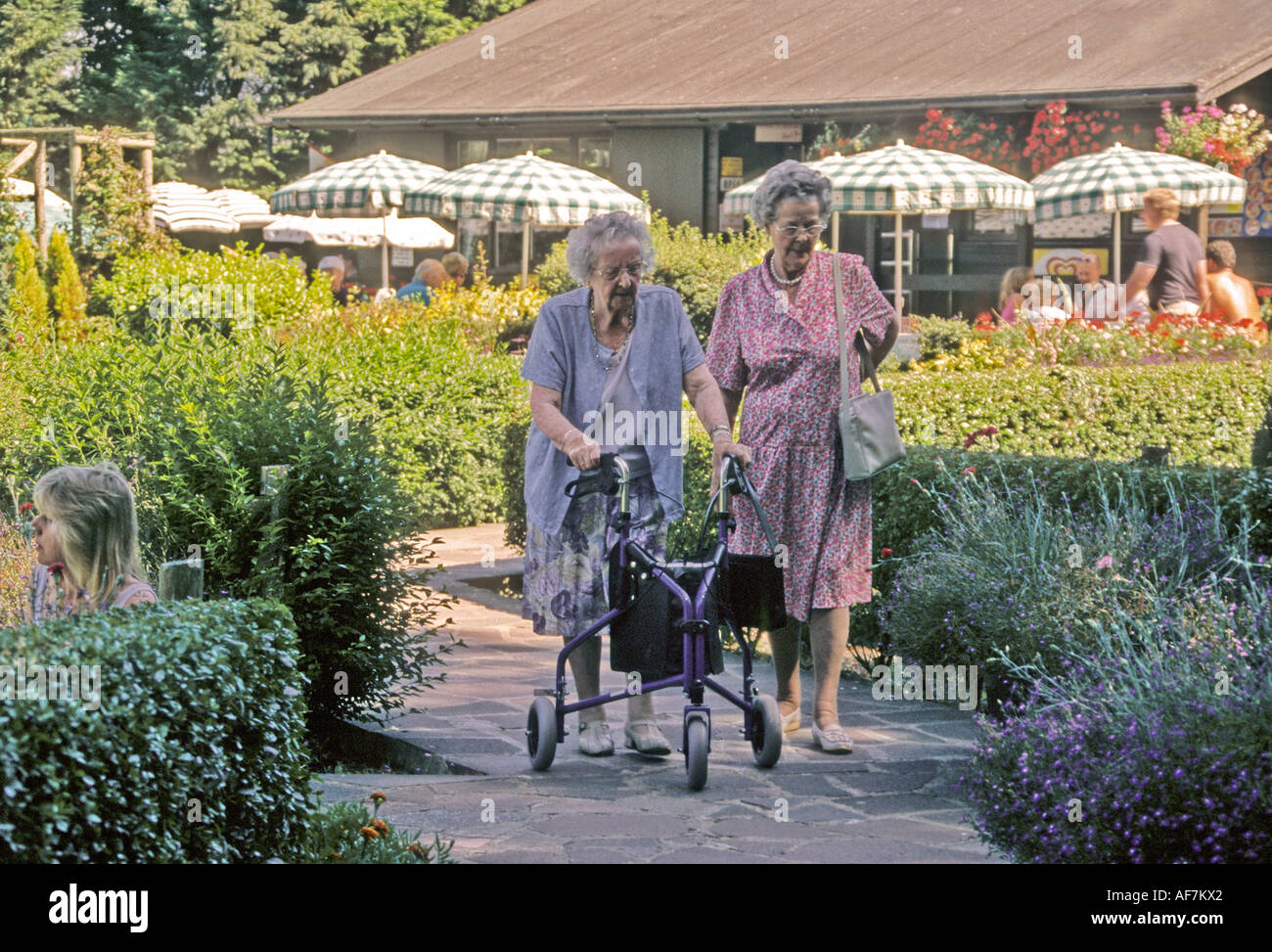 elderly women (one of them using a wheeled frame) walking through a ...