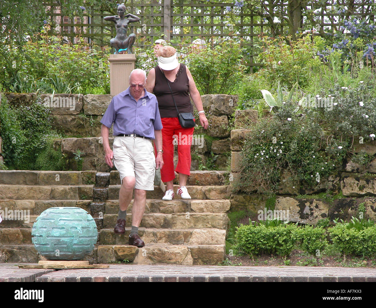 elderly couple coping with old rickety steps in Italian garden at Borde ...