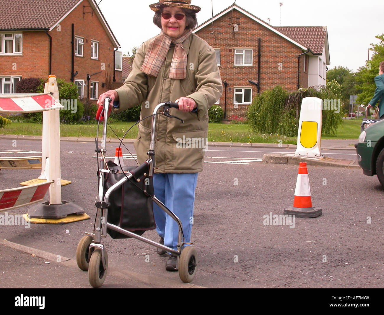 partially disabled elderly woman using wheeled frame crosssing the road ...