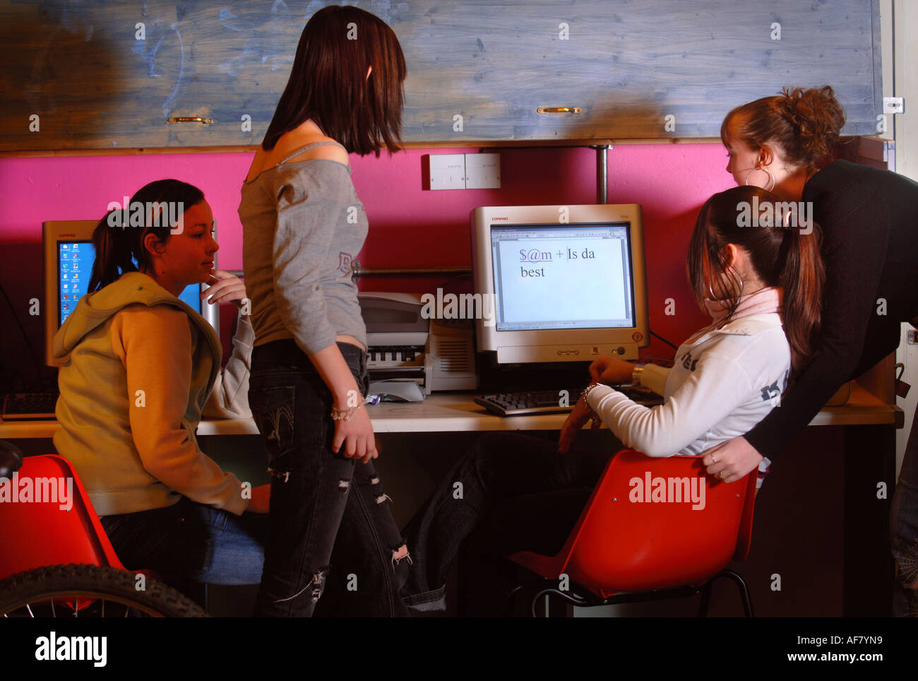 A GROUP OF FOUR TEENAGE GIRLS USING A COMPUTER IN A YOUTH CLUB UK Stock ...