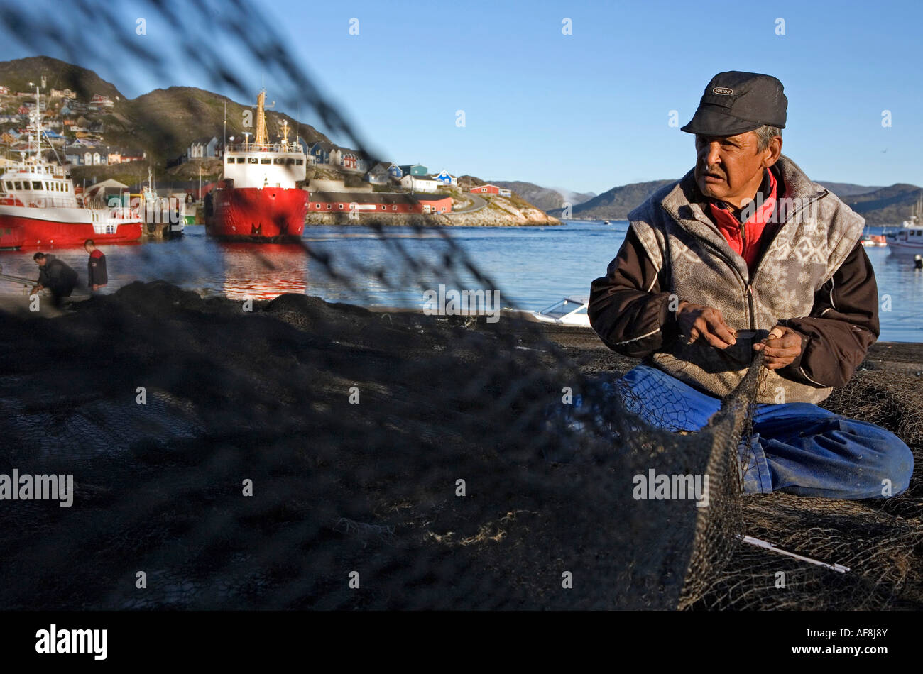 An eskimo, inuit at Qaqortoq (former Julianehab), repares a fishing net ...