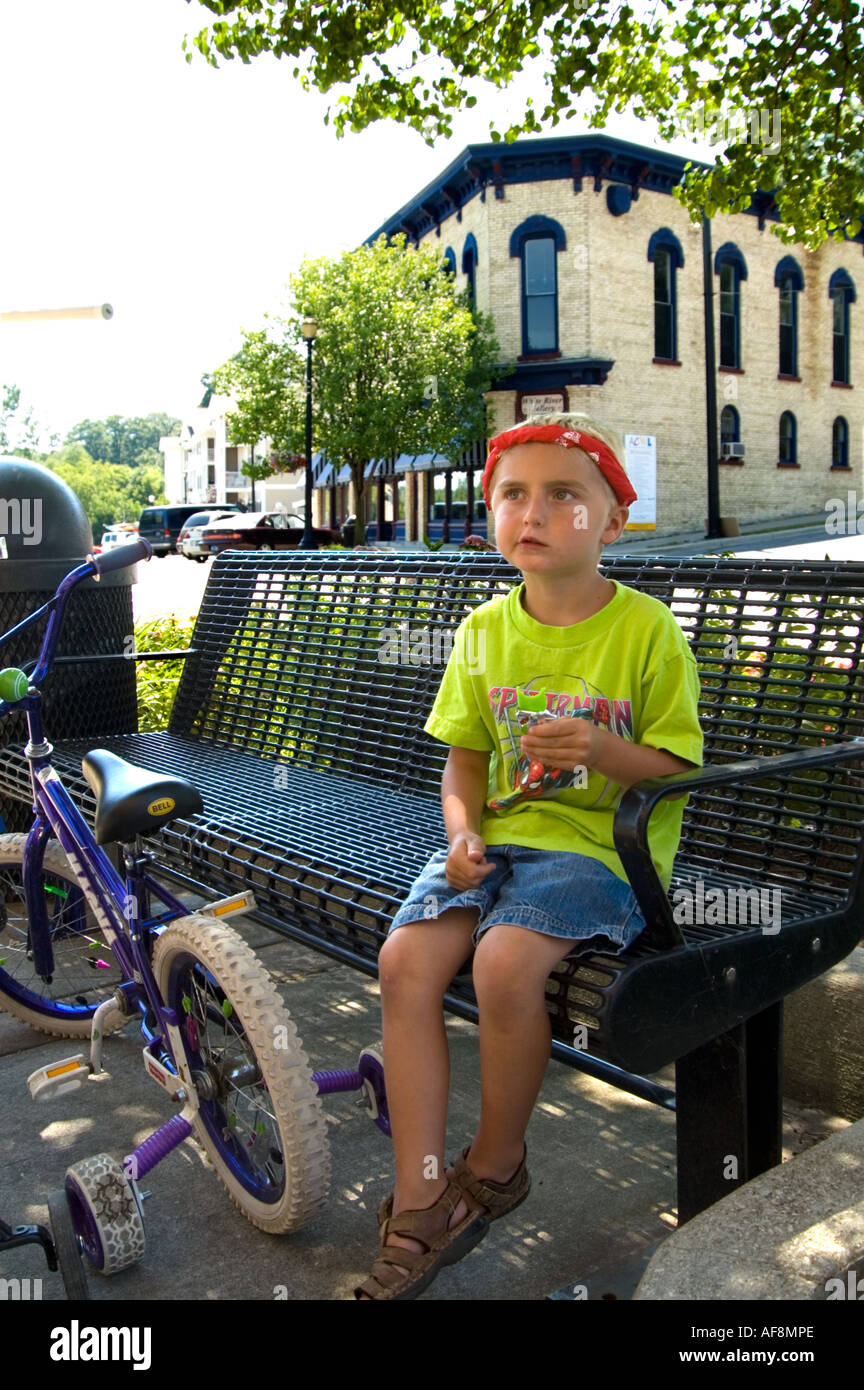 Boy eating candy on a sidewalk bench in downtown Montague MI Stock ...
