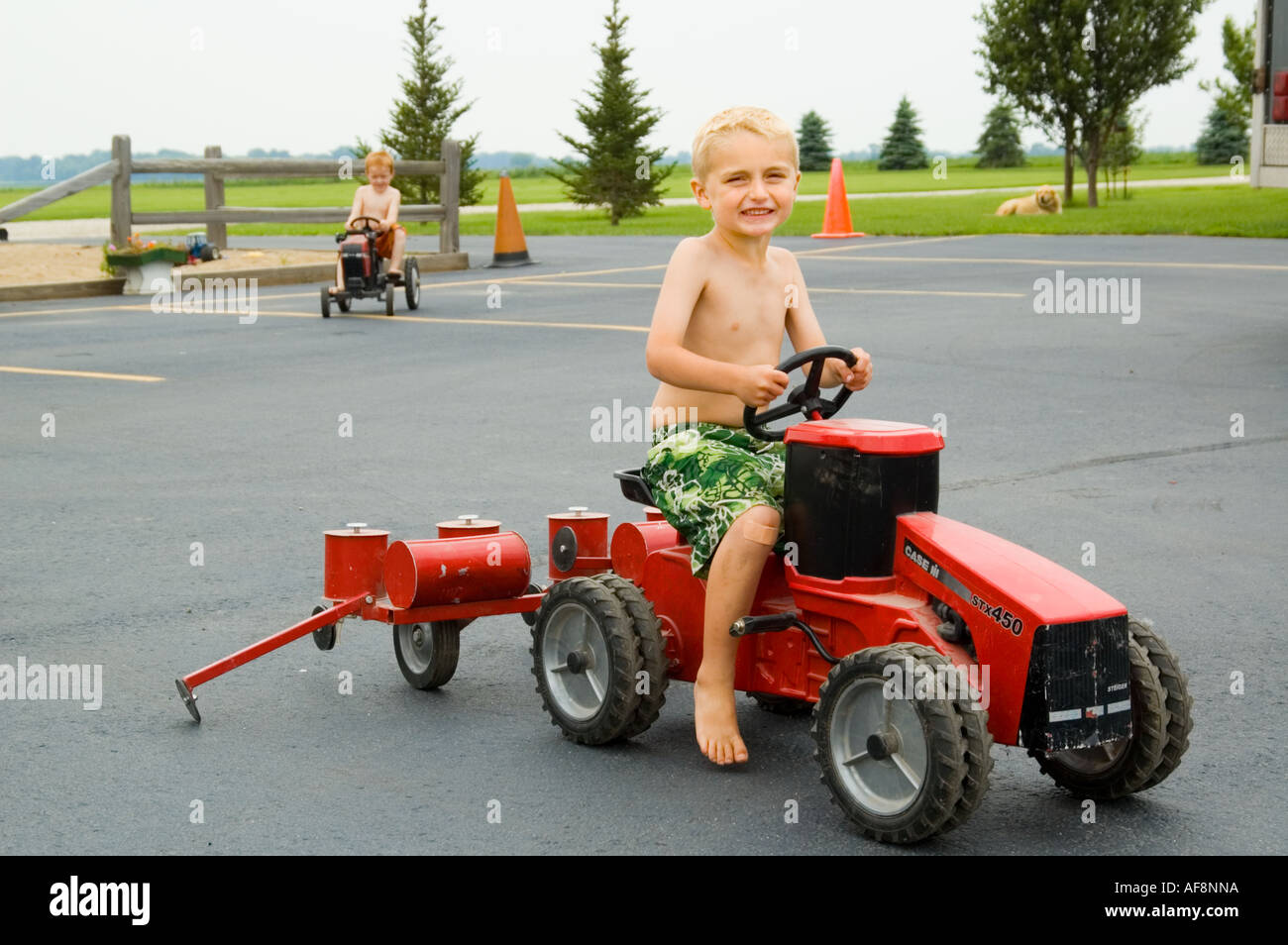 Boys pretend to plant crops in the parking area on the family farm in ...
