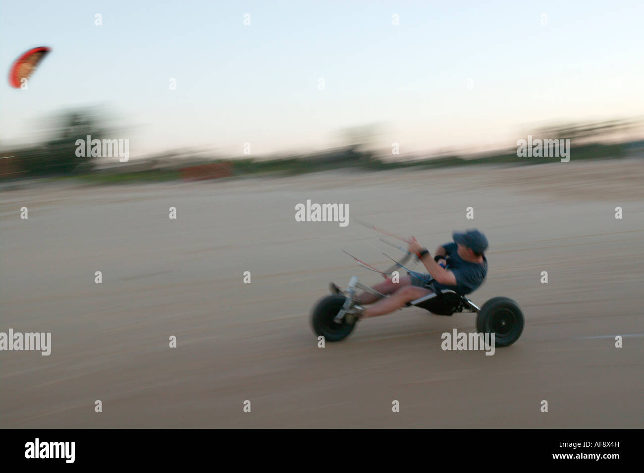 A kite buggy being driven down the beach at sunset Stock Photo - Alamy