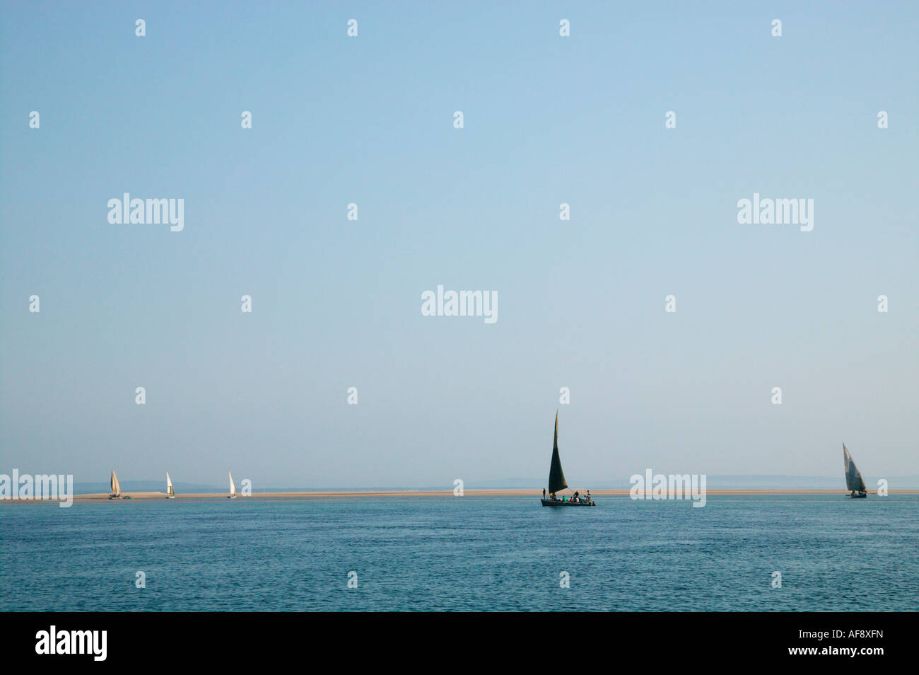 Dhows sailing on a narrow channel from Maxxixe towards the open sea ...