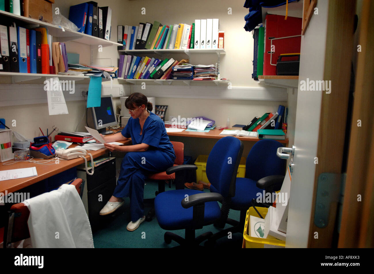 a crowded NHS hospital office filled with paperwork and illustrating ...