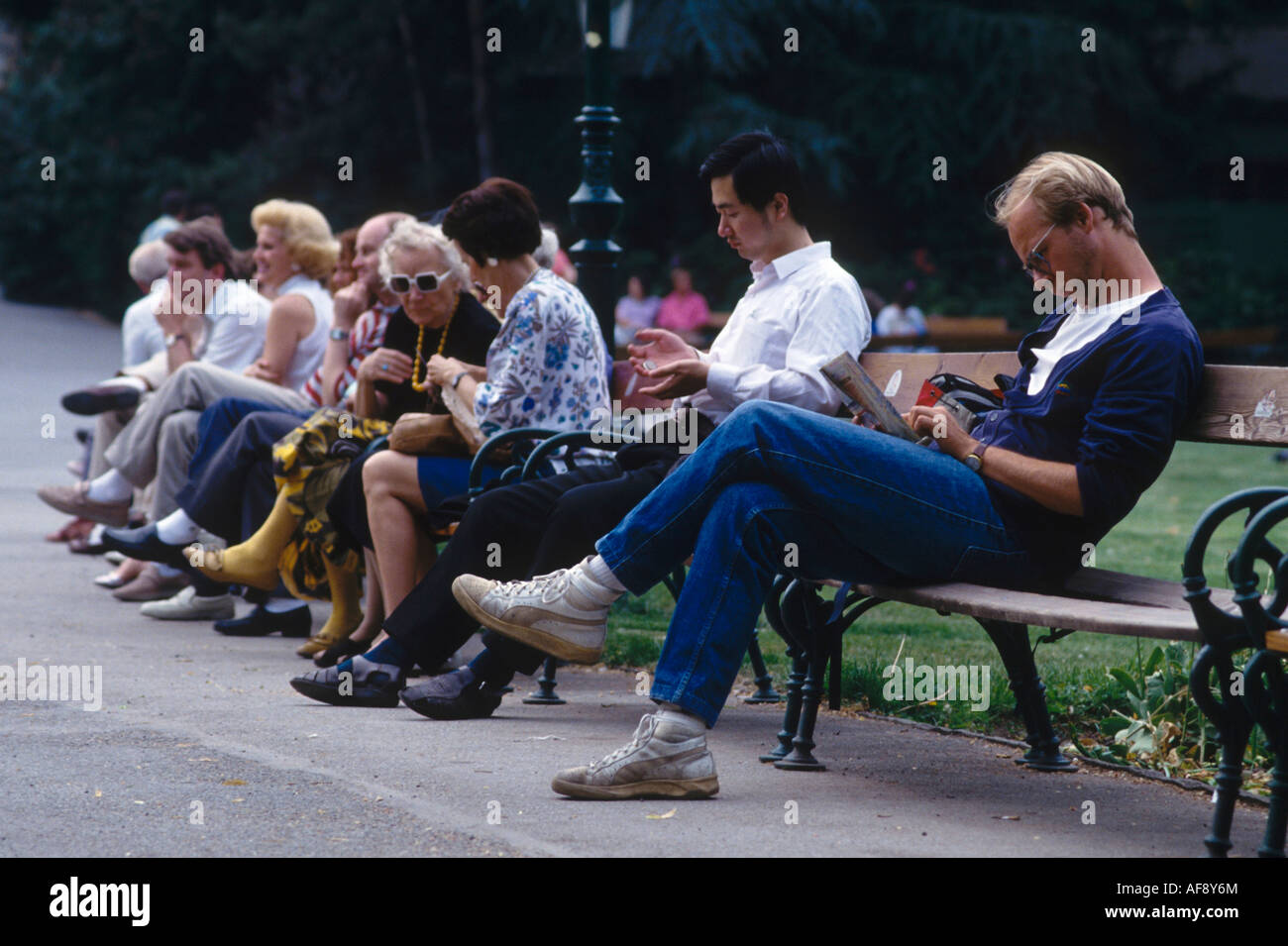 A multi cultural group of people relax on of benches in a park in Vienna Vienna Wien Austria ...