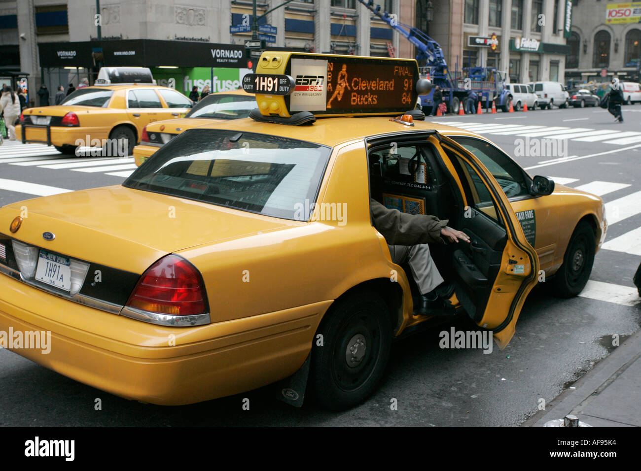 white caucasian passenger closes rear door of yellow cab on taxi rank ...
