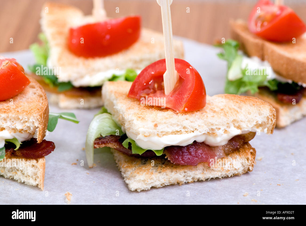 A gourmet BLT sandwich cut into wedges with a small tomato on top Stock ...