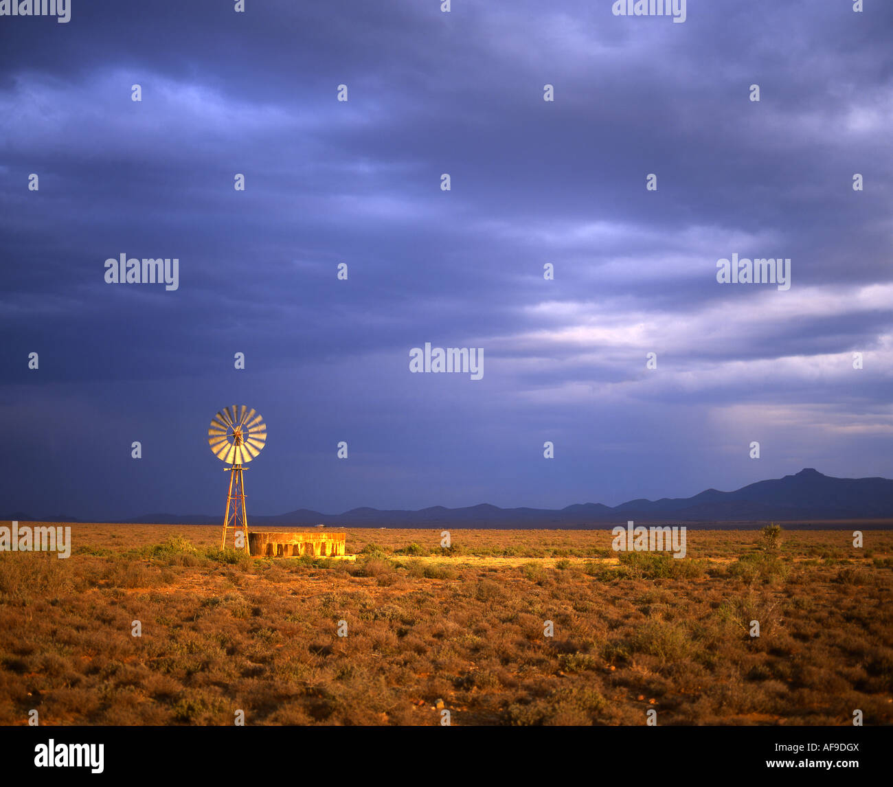 Rural scene with a lone windmill and water storage reservoir against a ...