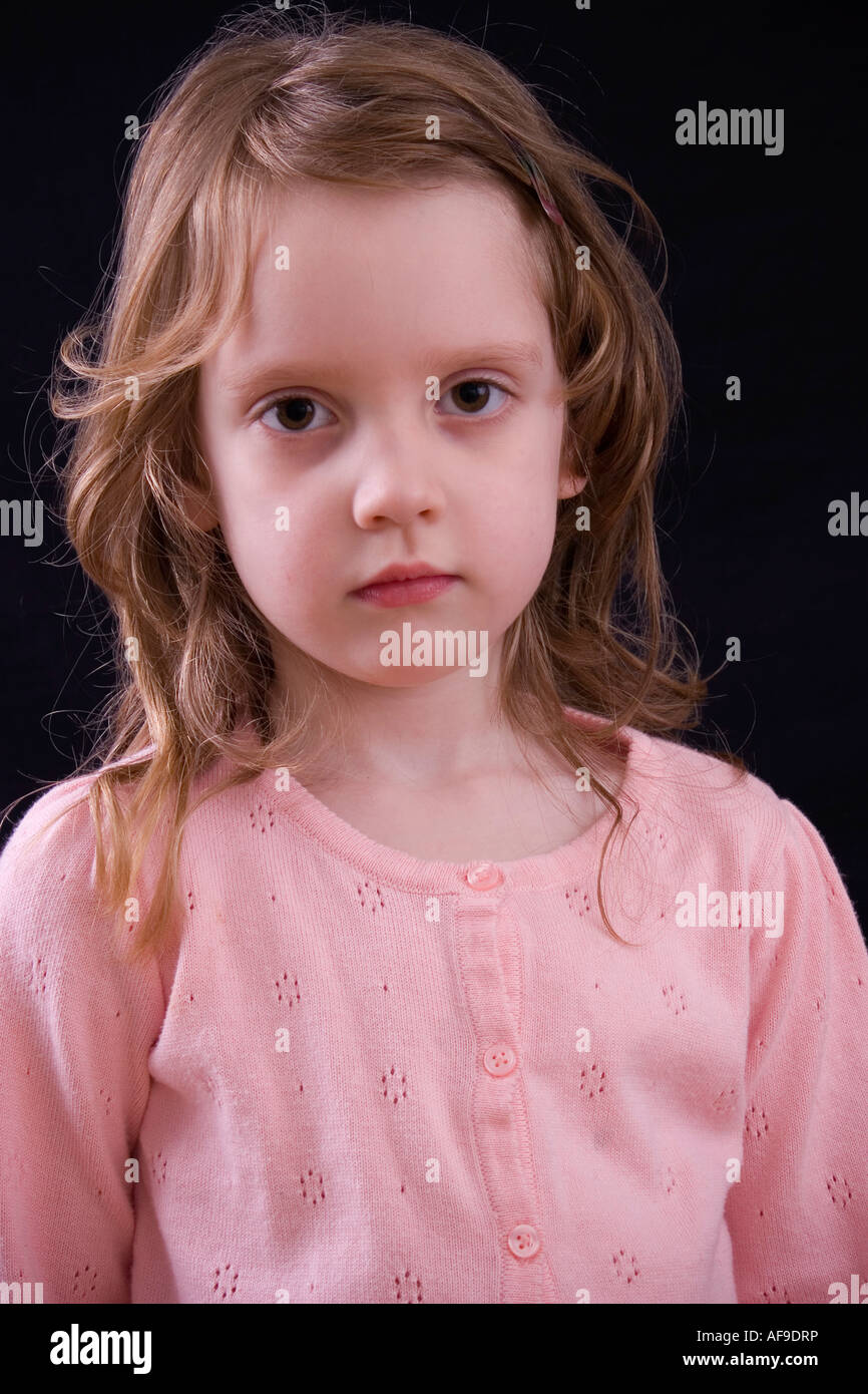 Portrait of a serious looking little girl on a black background Stock ...