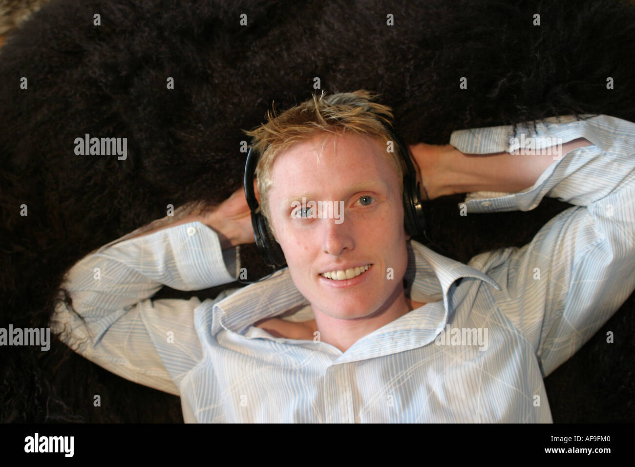 A Stock Photograph of a Man Laying Down on a Carpet Listening to Music ...