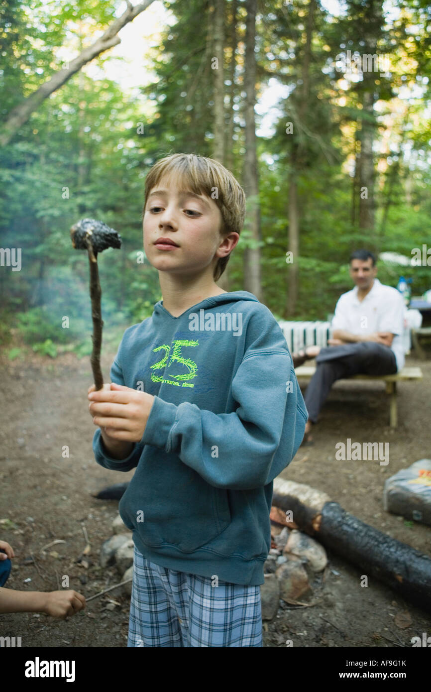 Little boy blowing out a burning marshmallow as dad looks on. Model ...