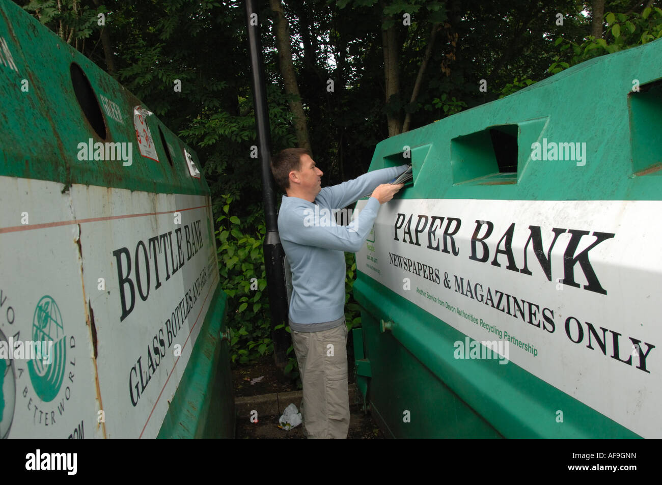 Man putting magazines into recycling bank in Bovey Tracey Devon England ...
