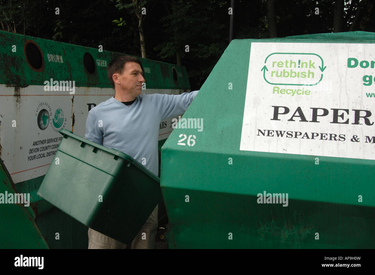 Man putting magazines into recycling bank in Bovey Tracey Devon England ...