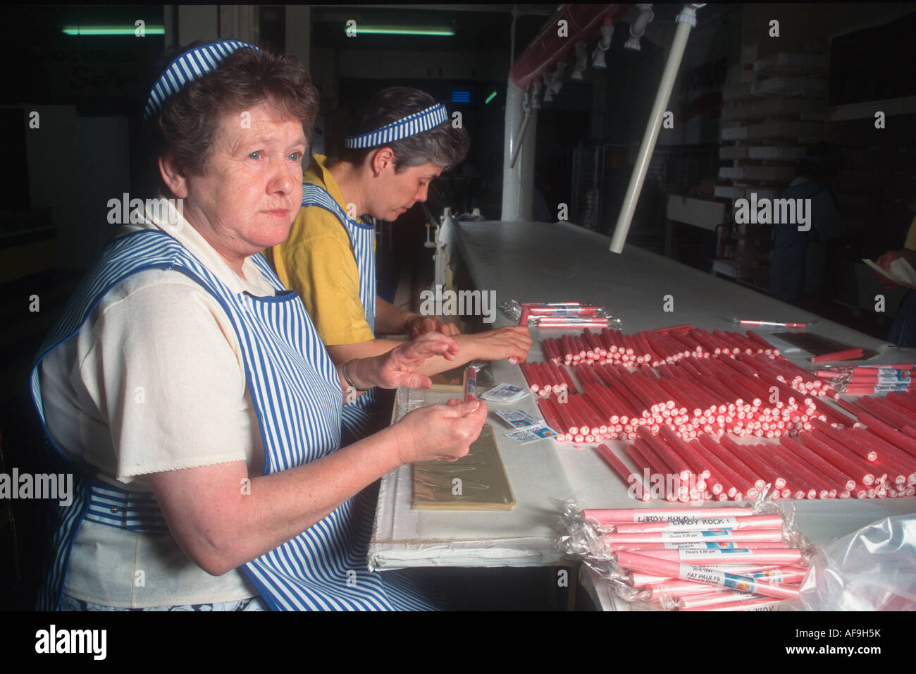 Two sweet factory workers sit wrapping sticks of candy rock Stock Photo ...
