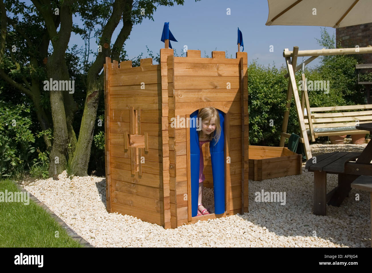 Young girl peeping out of wooden play castle Cotswolds UK Stock Photo ...