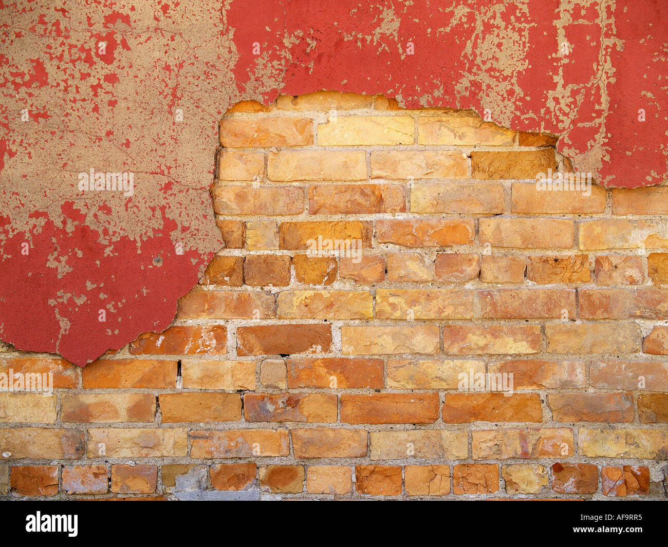 Painted red cement flaking off of an orange and yellow brick wall Stock ...