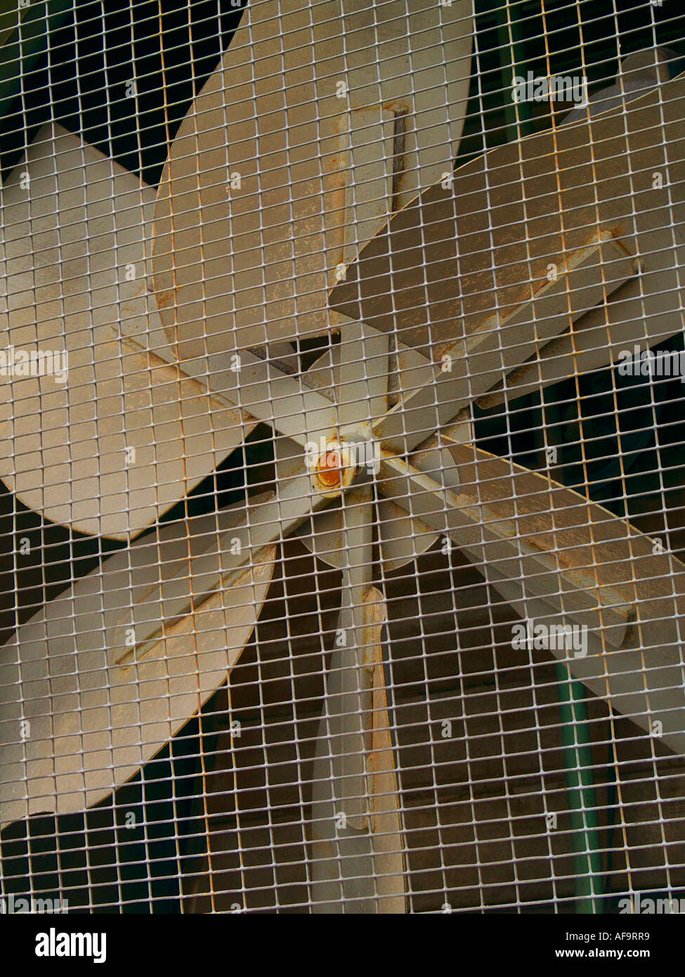 Extremely large industrial cooling fan behind a wire grate in moody ...