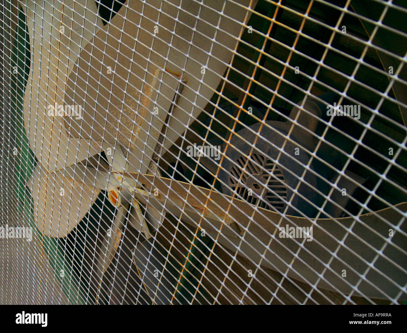 Extremely large industrial cooling fan behind a wire grate in moody ...