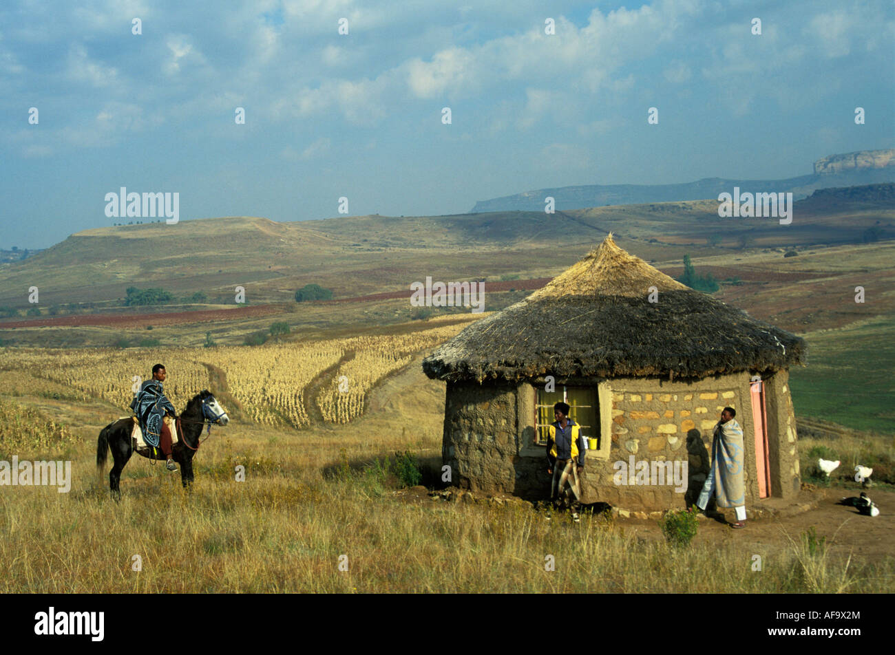 A Lesotho couple outside their homestead move towards an approaching ...